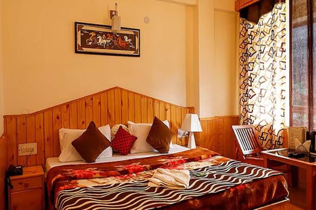 Quarto de hotel com cabeceira de madeira, colcha com padrão de zebra e um quadro na parede.