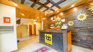 Uma receção com um letreiro 'fab hotels', uma estátua de Buda e um aviso de 'proibido fumar'.