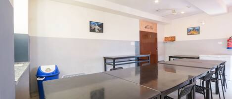 Uma sala de conferência com uma mesa comprida e cadeiras, uma lixeira e uma porta com a inscrição 'SAVELS'.