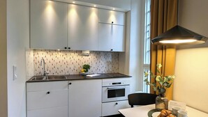 Cozinha compacta com pia, fogão e área de jantar com mesa posta para dois.