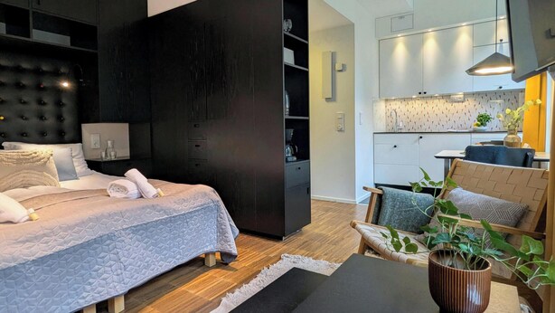 Quarto moderno com cama, mesa de cabeceira e pequena escrivaninha.