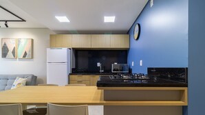 Cozinha moderna com geladeira, micro-ondas, fogão e área de jantar com cadeiras e mesa.