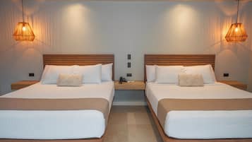 Quarto duplo com duas camas, cada uma com cabeceira de madeira, roupa de cama branca e uma pequena mesa de cabeceira com abajur.