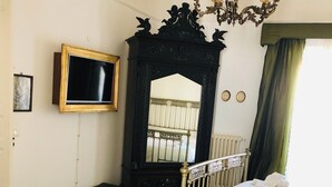 Quarto com uma cama, um espelho grande, televisão e piso estampado.