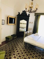 Quarto com uma cama, um espelho grande, televisão e piso estampado.