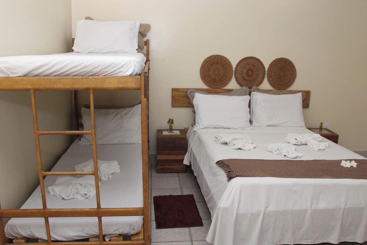 Quarto com beliche, uma cama individual e uma mesa de cabeceira.