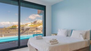 Quarto moderno com cama grande, vista para uma piscina e varanda.
