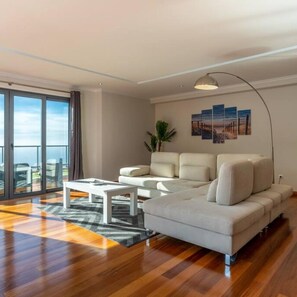 Uma sala de estar moderna com um sofá seccional, uma mesa de centro e uma janela grande com vista para o exterior.