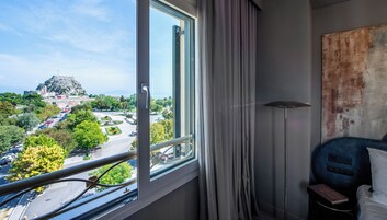 Quarto com uma janela ampla com vista para a paisagem urbana, uma luminária moderna e uma cadeira.