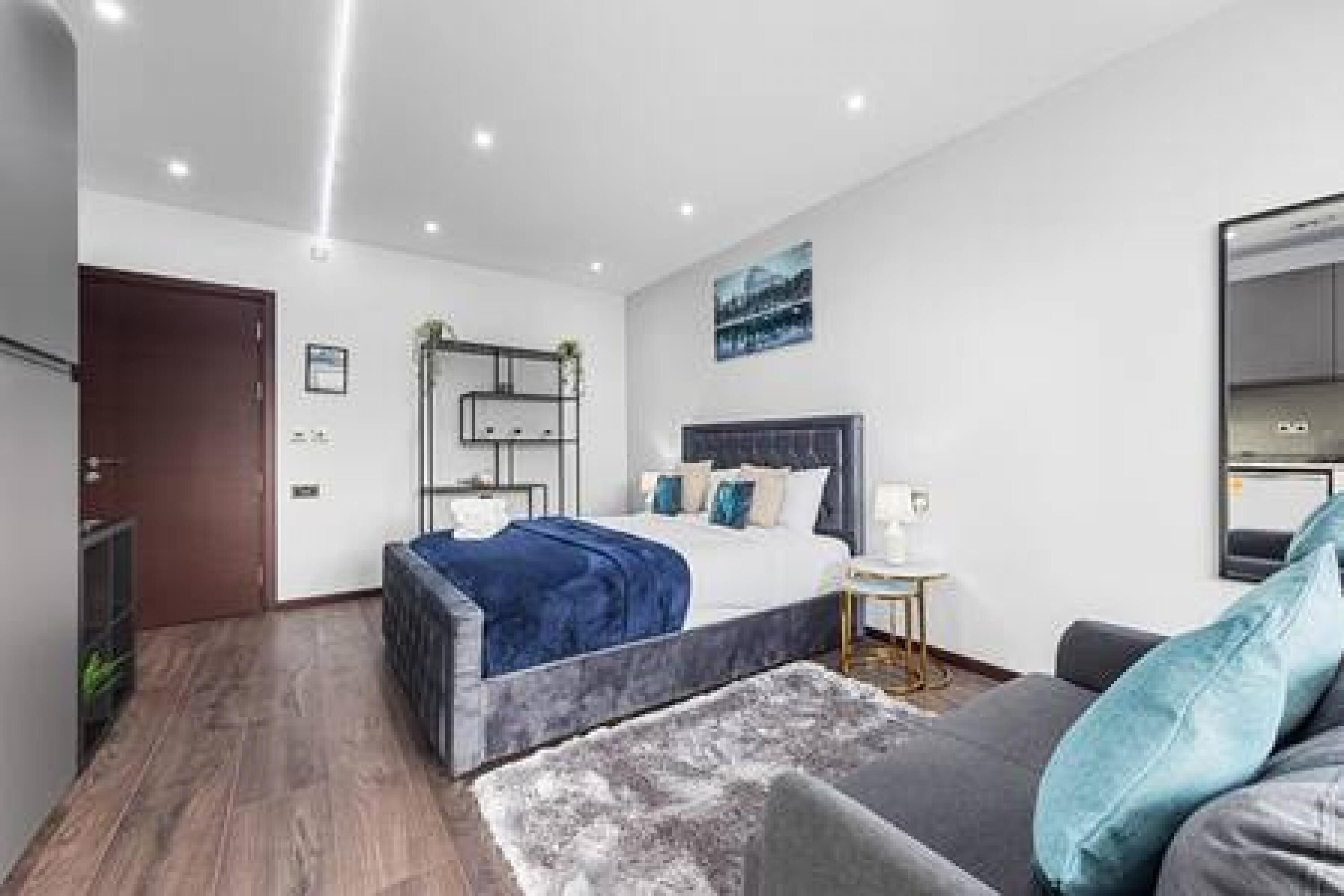Quarto moderno com cama, mesa de cabeceira e um espelho grande.