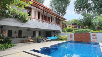 Uma casa de dois andares com piscina, varanda e jardim.