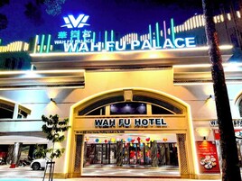 Exterior do Hotel Wah Fu Palace, com entrada notável e sinalização iluminada.