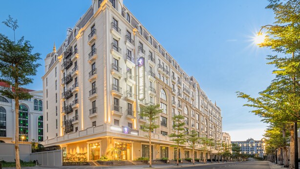 Um hotel com vários andares, design arquitetônico clássico, com varandas e grandes janelas.