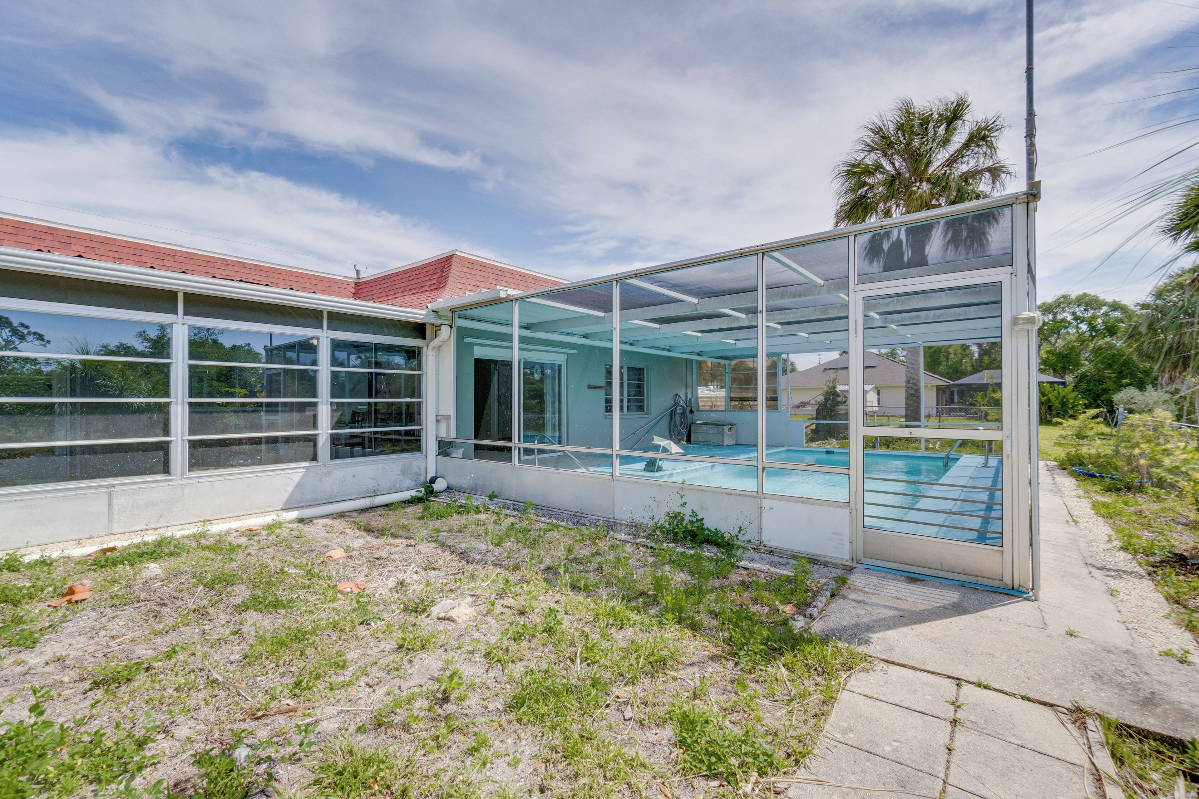 Uma casa moderna com piscina envidraçada, janelas amplas e telhado vermelho.