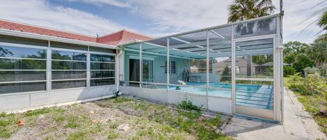 Uma casa moderna com piscina envidraçada, janelas amplas e telhado vermelho.