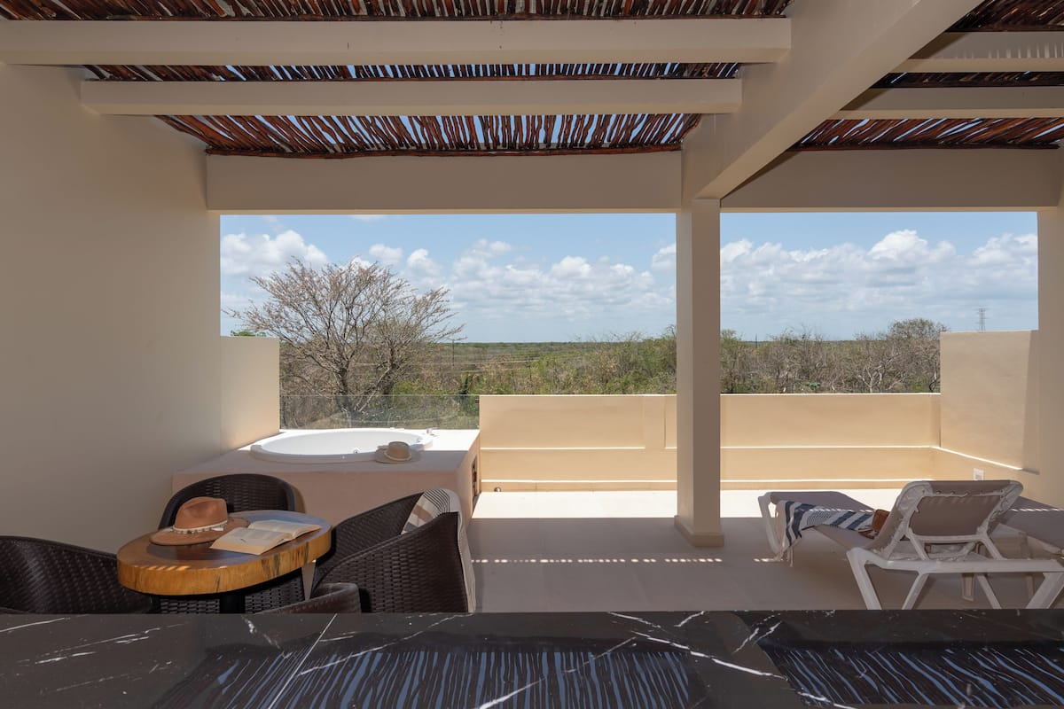 Uma varanda com hidromassagem, mobiliário de vime e vista para a paisagem.