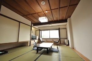 Um quarto japonês tradicional com tatames, teto de madeira baixo e portas deslizantes.