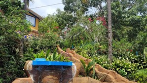 Uma área de recreação aquática com uma grande escultura de elefante, cercada por pedras e plantas.