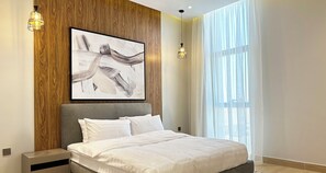 Quarto moderno com cama grande, painel de parede em madeira e uma grande pintura abstrata.