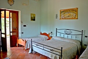 Quarto com duas camas de solteiro, porta de madeira e chão de azulejos.