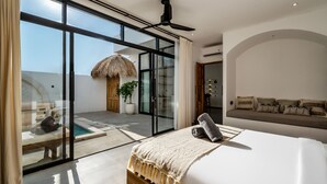 Quarto moderno com uma cama grande, ventilador de teto e vista para uma piscina e área de estar ao ar livre.