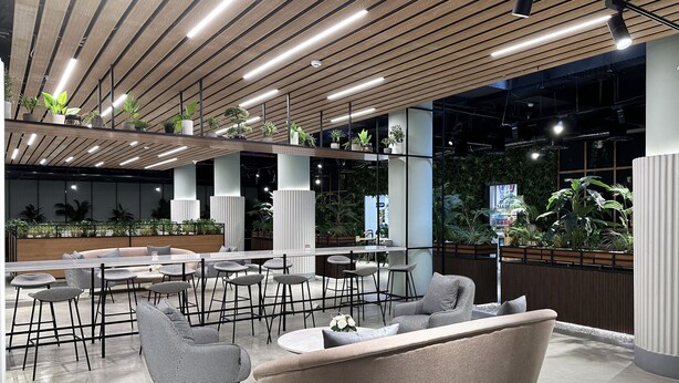Espaço interno moderno com área de bar, assentos e plantas.