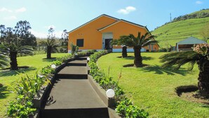 Um edifício amarelo com um caminho de concreto que leva à entrada.