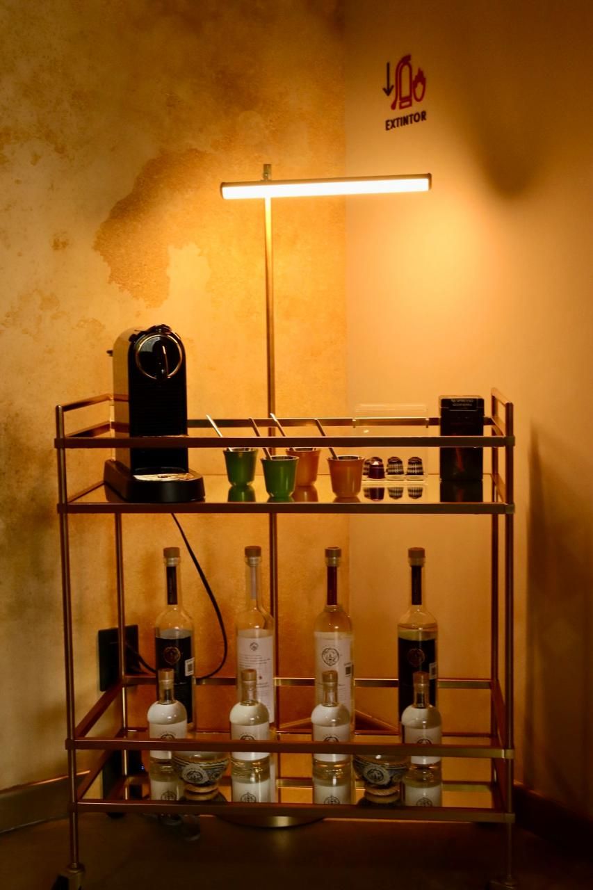 Estante de metal com várias garrafas, uma máquina de café e um aviso indicando um extintor.