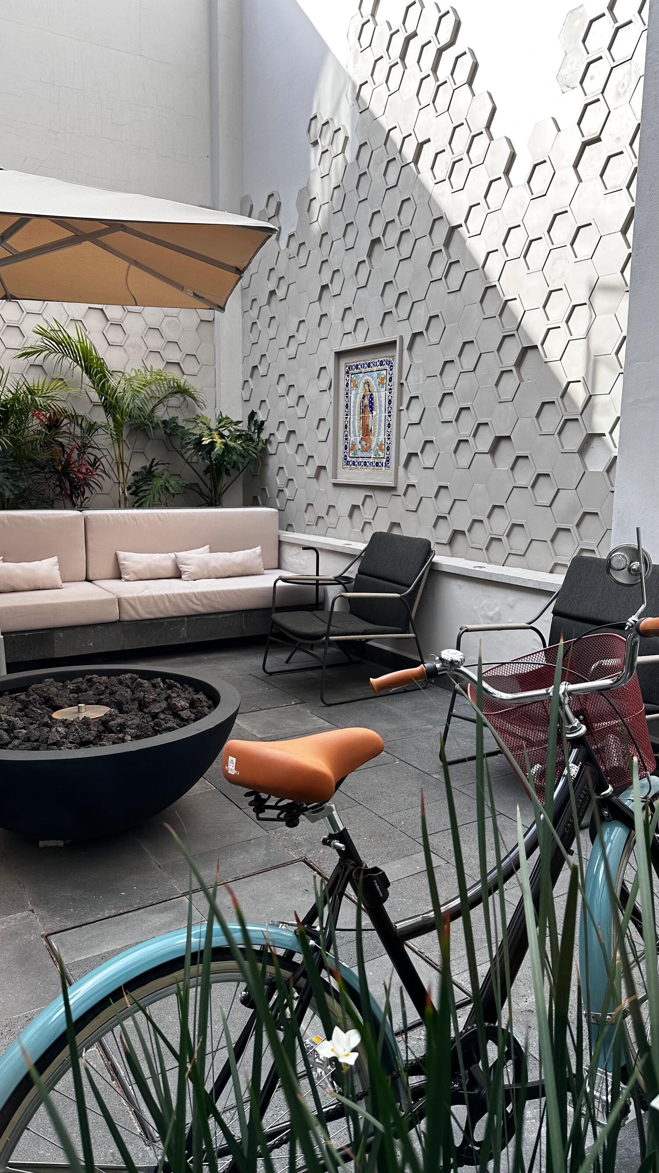 Uma área de estar moderna ao ar livre, com um design de parede hexagonal, uma bicicleta preta e um braseiro preto.