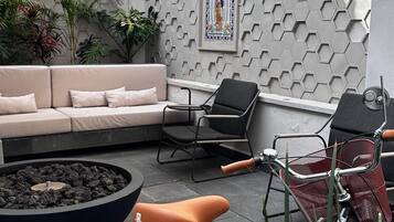 Uma área de estar moderna ao ar livre, com um design de parede hexagonal, uma bicicleta preta e um braseiro preto.