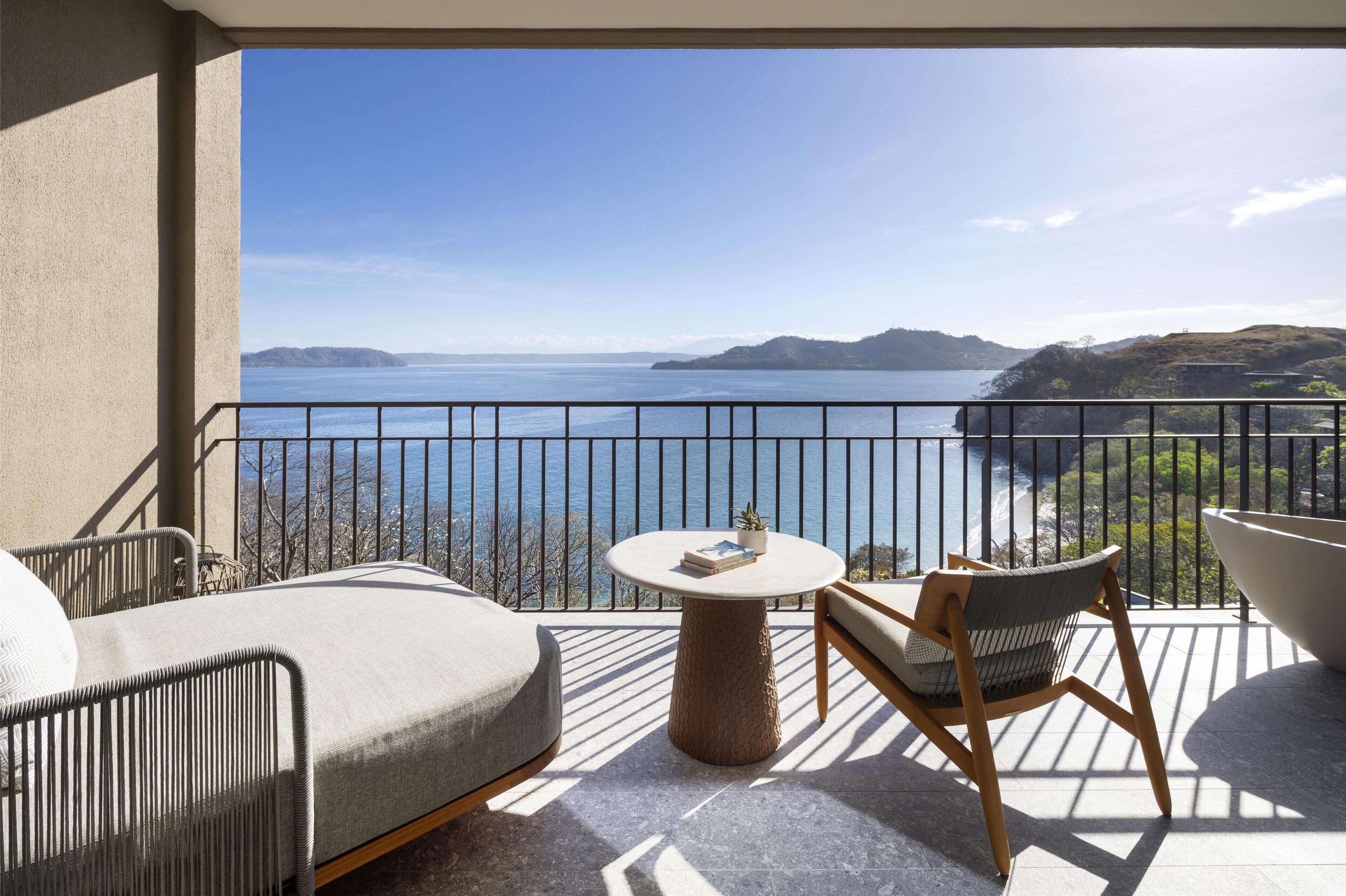 Varanda com vista para o mar, uma mesa redonda e duas cadeiras.