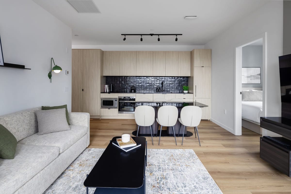 Uma sala de estar moderna com sofá, mesa de centro e área de jantar com cadeiras.
