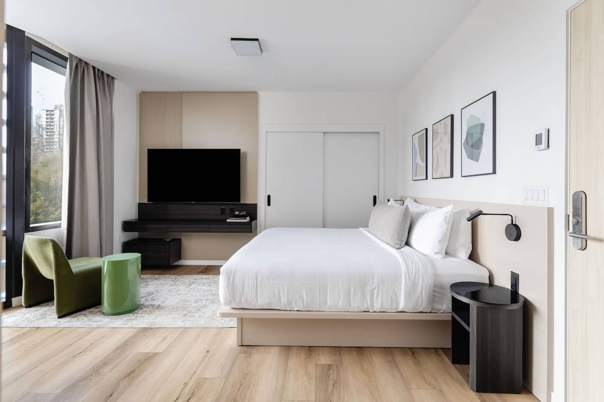 Quarto moderno com cama, TV, escrivaninha e cadeira.