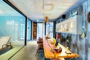 Uma sala de jantar moderna com uma mesa de madeira comprida, cadeiras e um lustre pendurado.