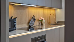 Uma cozinha moderna com micro-ondas embutido, suporte para facas, um vaso com flores e uma torneira elegante.