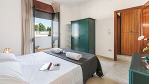 Quarto de hotel com cama, guarda-roupa, escrivaninha e vista para o exterior.