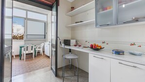Uma cozinha com armários brancos, micro-ondas e uma fruteira no balcão.