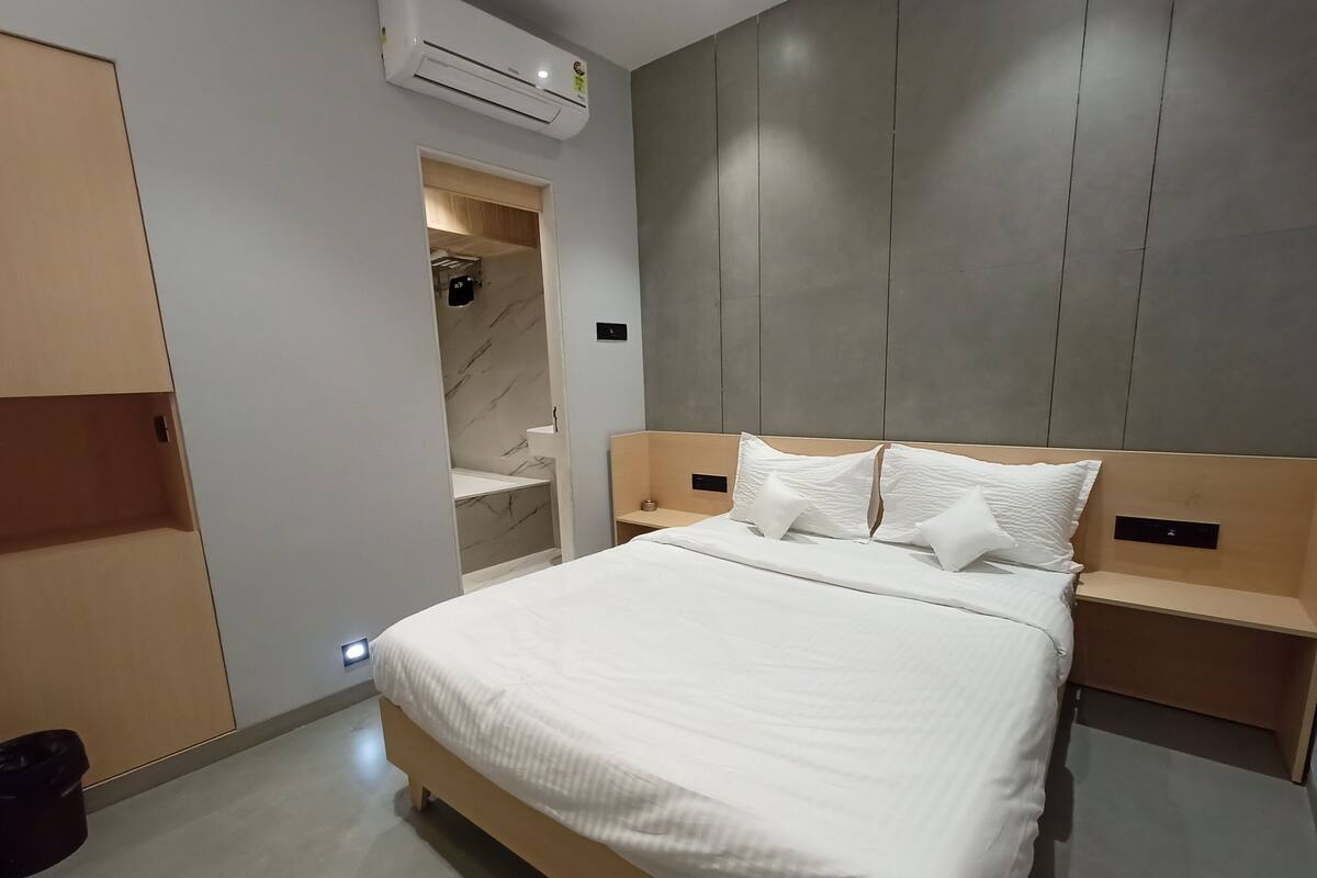 Quarto moderno com cama grande, cabeceira de madeira e armário embutido.