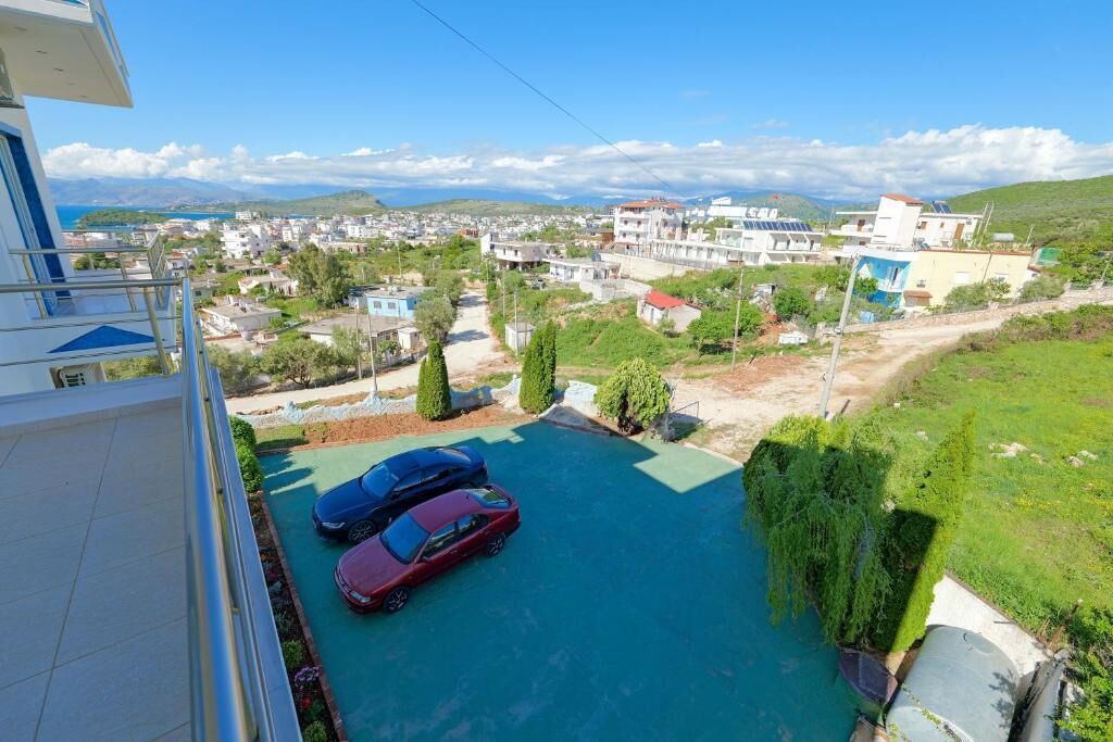 Zona residencial com piscina, carros estacionados e vista para uma cidade ao longe.