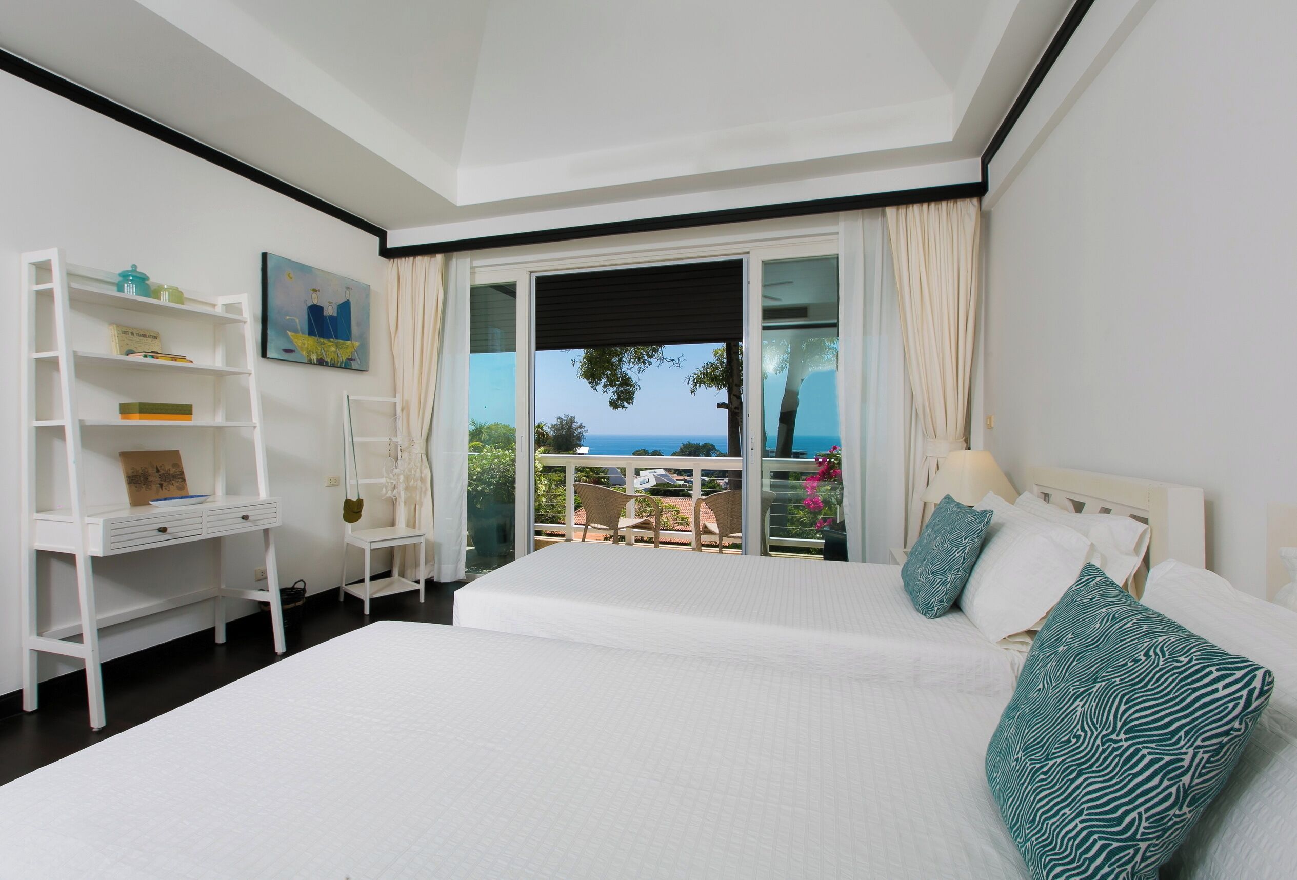 Quarto de hotel com uma cama grande, uma escrivaninha e vista para o mar.