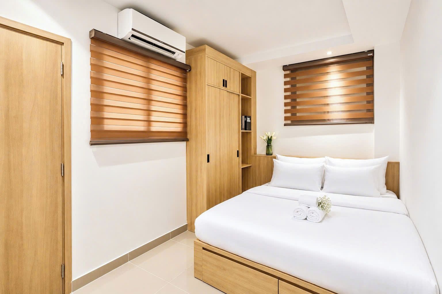 Quarto com cama, guarda-roupa de madeira e ar condicionado.
