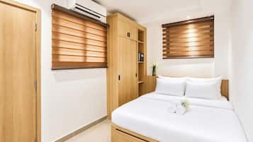 Quarto com cama, guarda-roupa de madeira e ar condicionado.