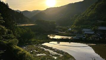 Uma paisagem serena com um rio, colinas e edifícios tradicionais.