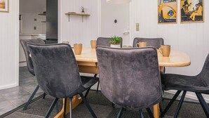 Uma sala de jantar com uma mesa redonda, seis cadeiras e um lustre.