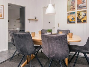 Uma sala de jantar com uma mesa redonda, seis cadeiras e um lustre.