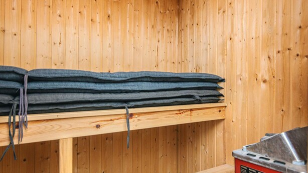 Uma sala de sauna com paredes de madeira, um banco e equipamento de sauna.