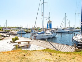 Marina com vários barcos atracados, um cais de madeira e uma pequena torre.
