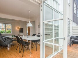 Uma área de refeições moderna com uma mesa branca, cadeiras pretas e uma janela grande.