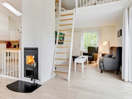 Um interior moderno com lareira, escada de madeira, área de estar e cozinha.