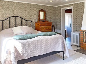 Quarto com cama, penteadeira, espelho e radiador.